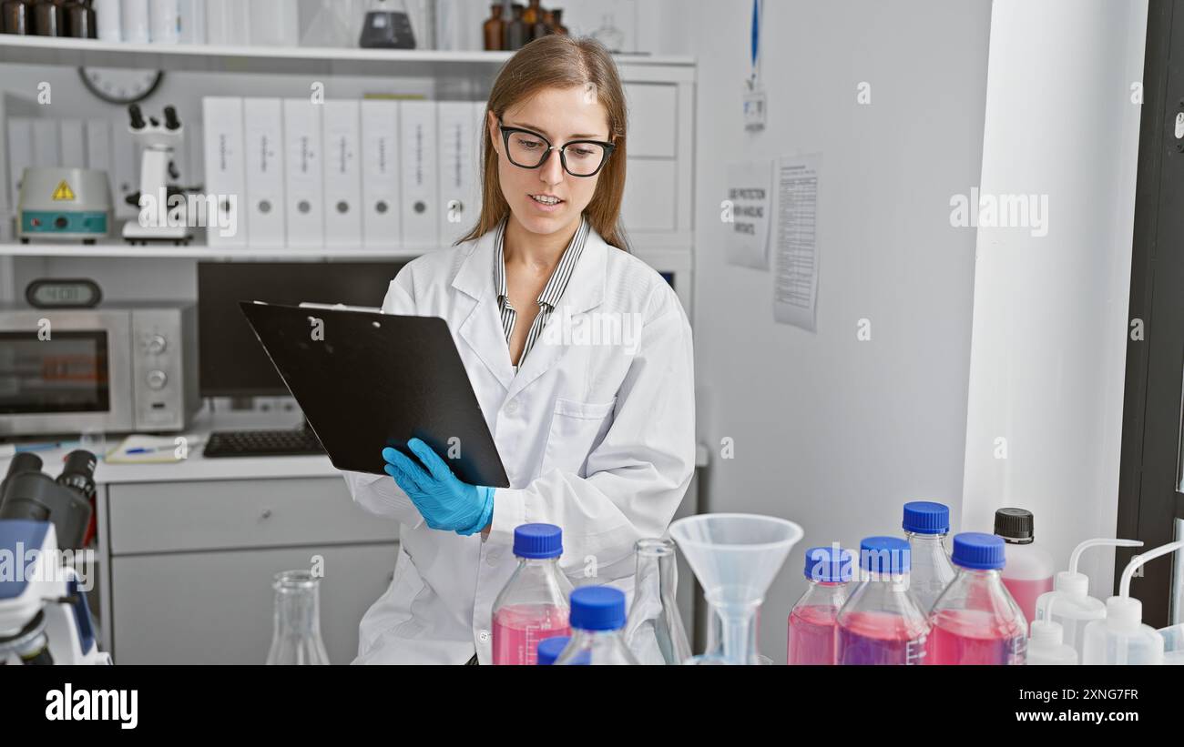 A young woman scientist carefully reviews data on a clipboard in a well ...