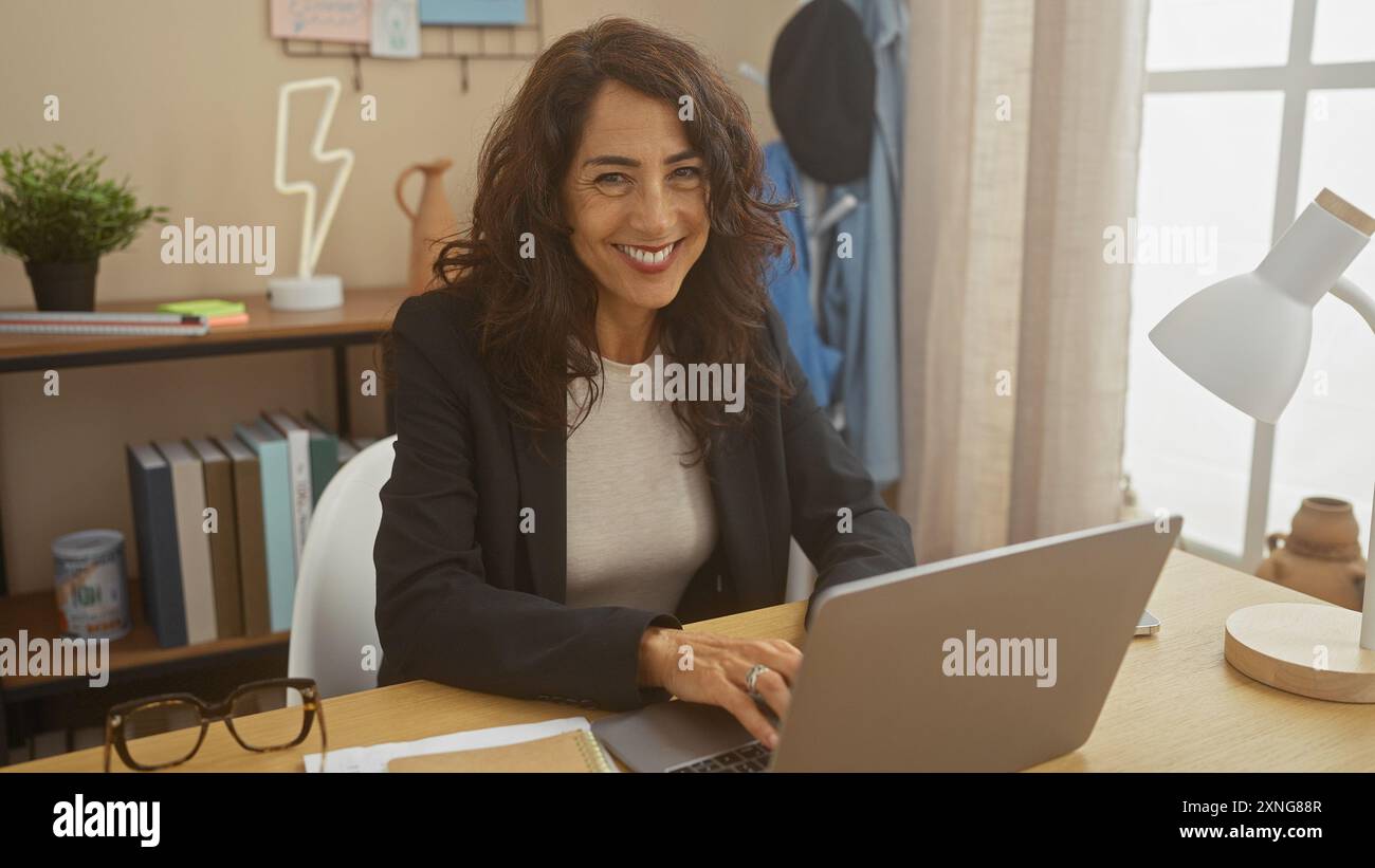Smiling woman working on laptop in modern home office setup Stock Photo ...