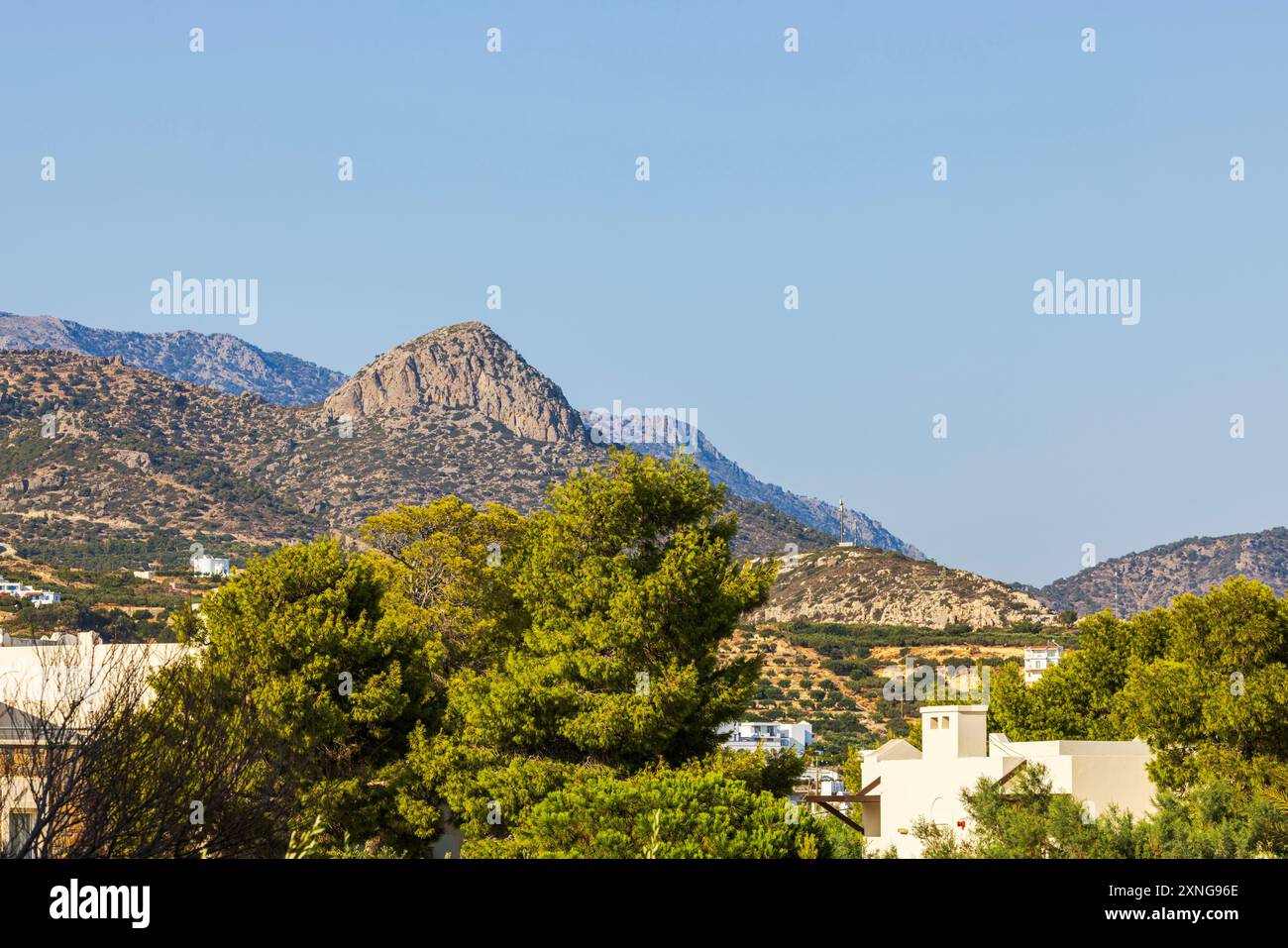 Mountain landscape with green trees and white buildings in foreground ...