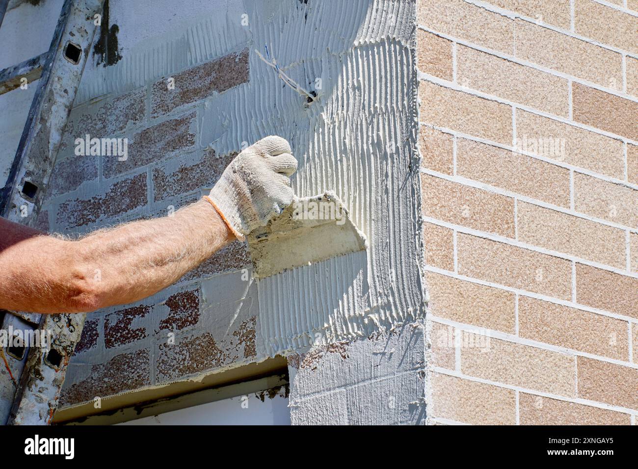 Using notched trowel, construction worker applies an even layer of ...