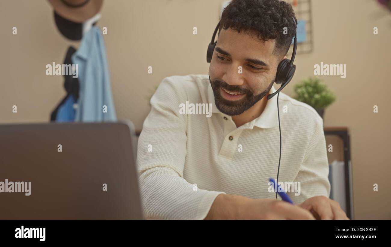 Hispanic man with beard smiling while taking notes at home, showcasing ...
