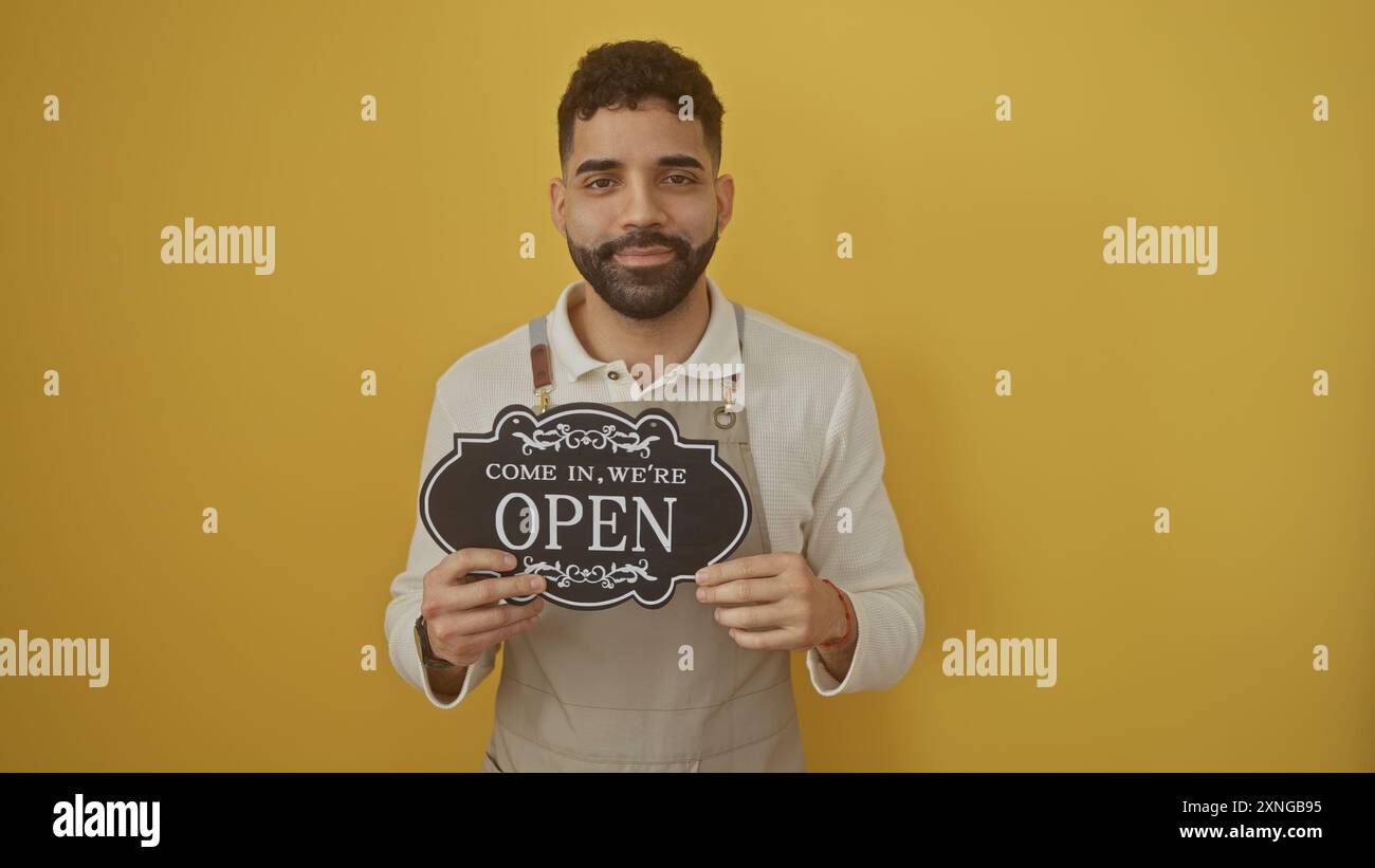 Handsome young hispanic man holding an open sign with a yellow ...