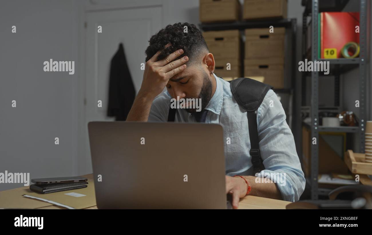 Hispanic man frustrated in a detective office with laptop, files, beard ...