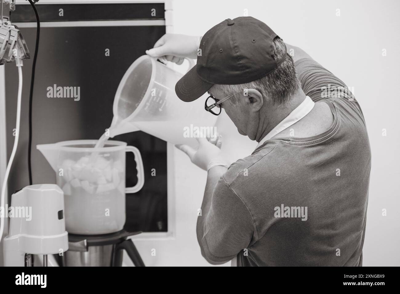 Scientist pours liquid from a cylinder into a beaker in a serious black ...