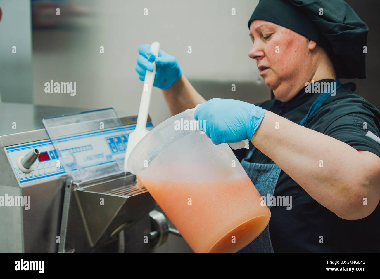 Chef is carefully pouring a large container of ingredients into a ...