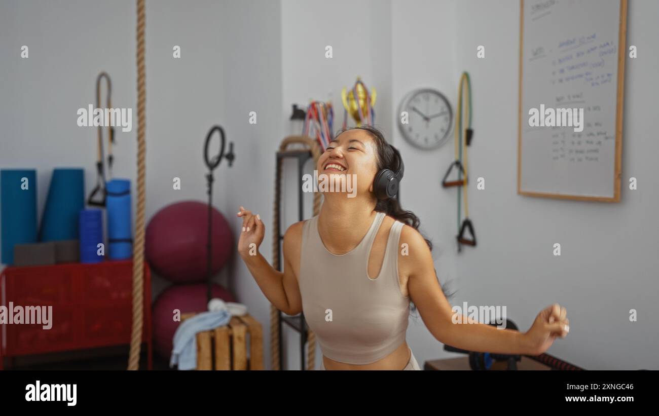 Young asian woman enjoying exercise in a gym, smiling happily while ...