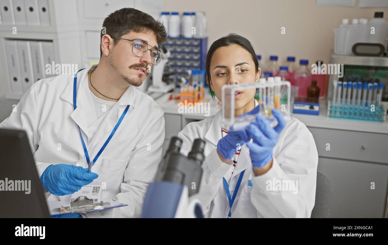 Two scientists, a man and a woman, examine a test tube together in a ...