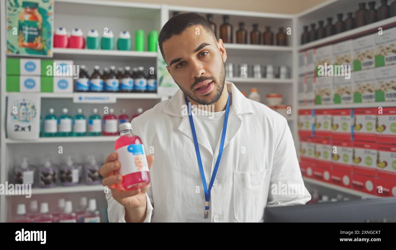A young hispanic male pharmacist holding a medication bottle stands in ...