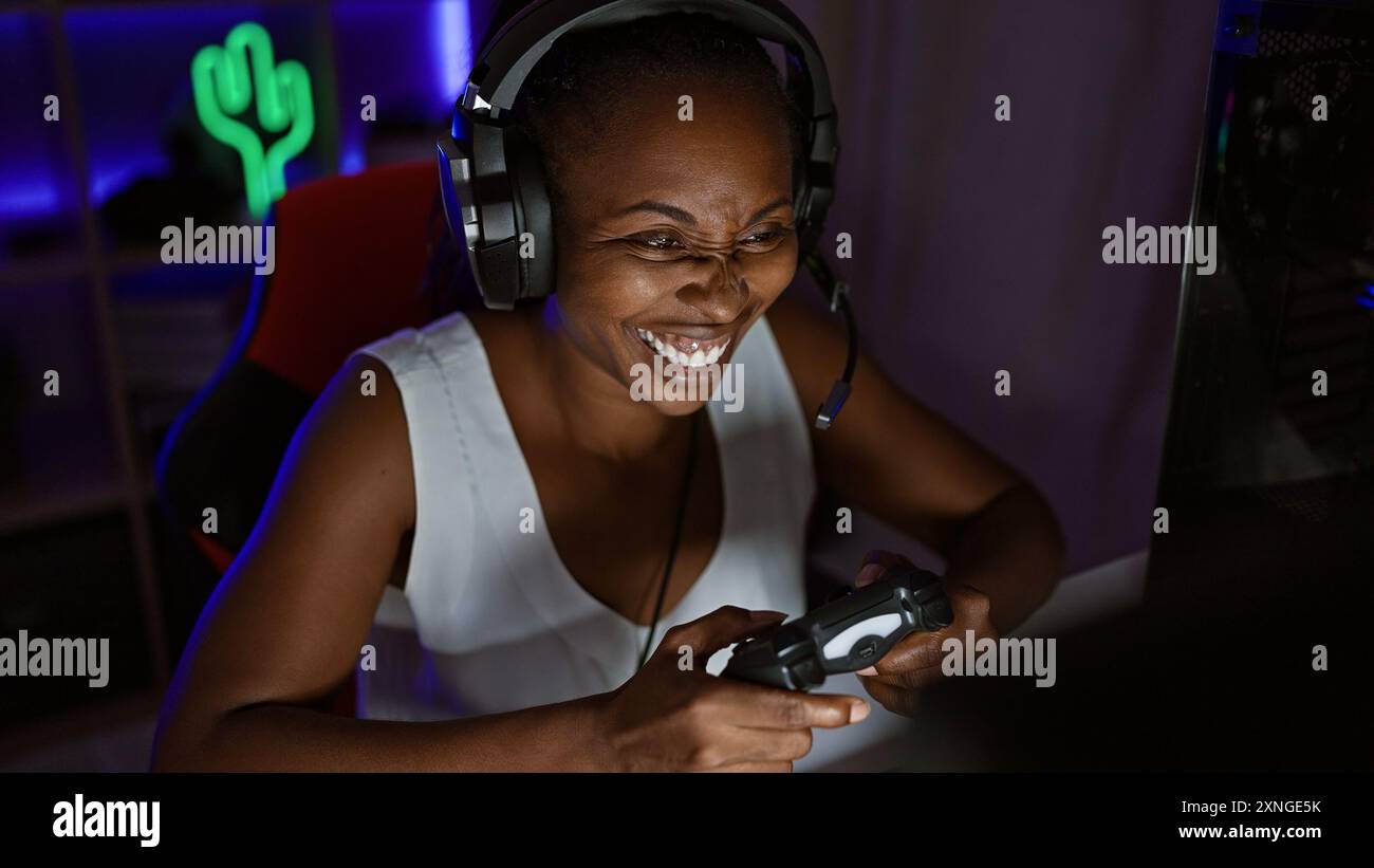 Smiling african american woman enjoying gaming at night in a dark room ...