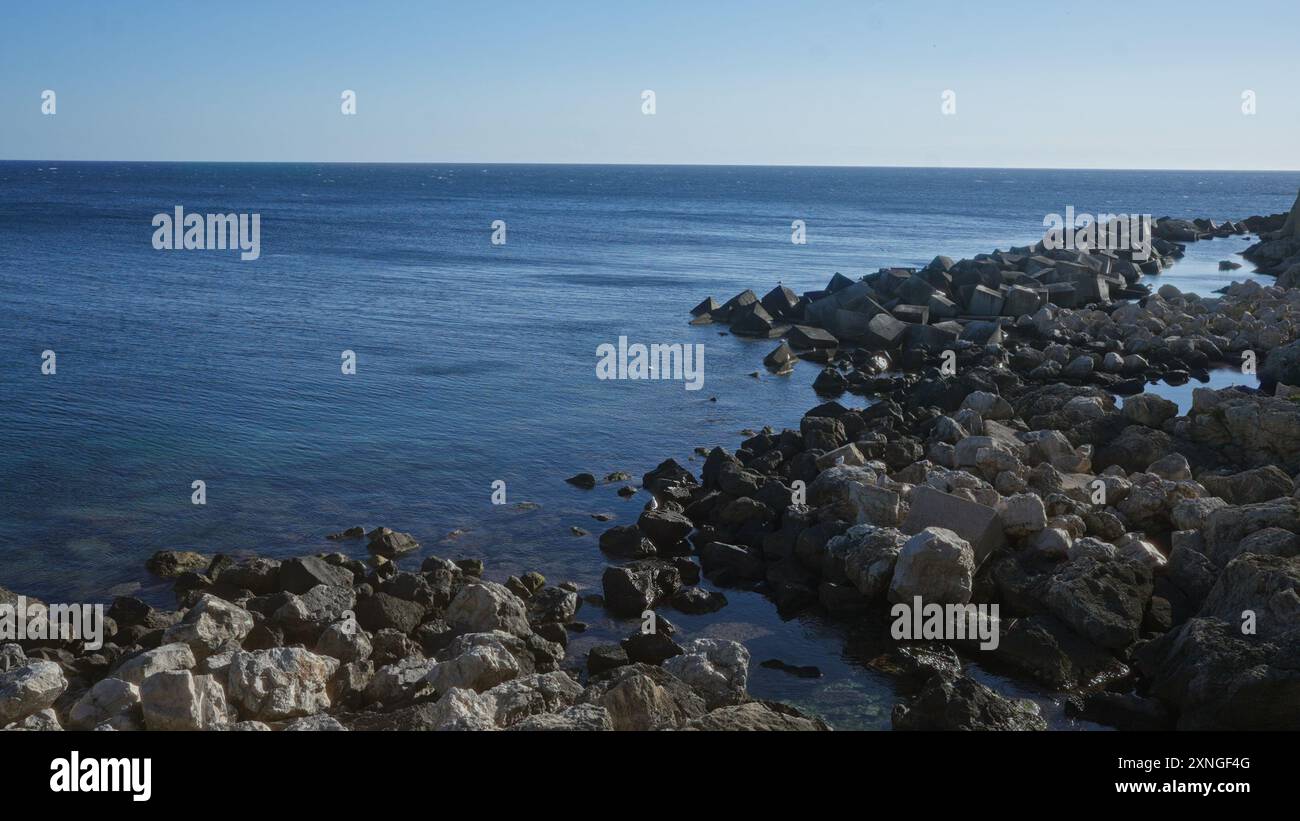 Rocky shoreline with clear blue water and scattered boulders in ...