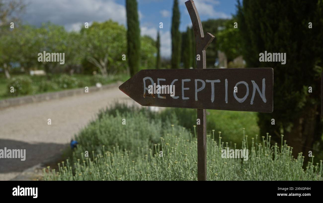 An outdoor reception sign in a lush garden with a gravel path ...