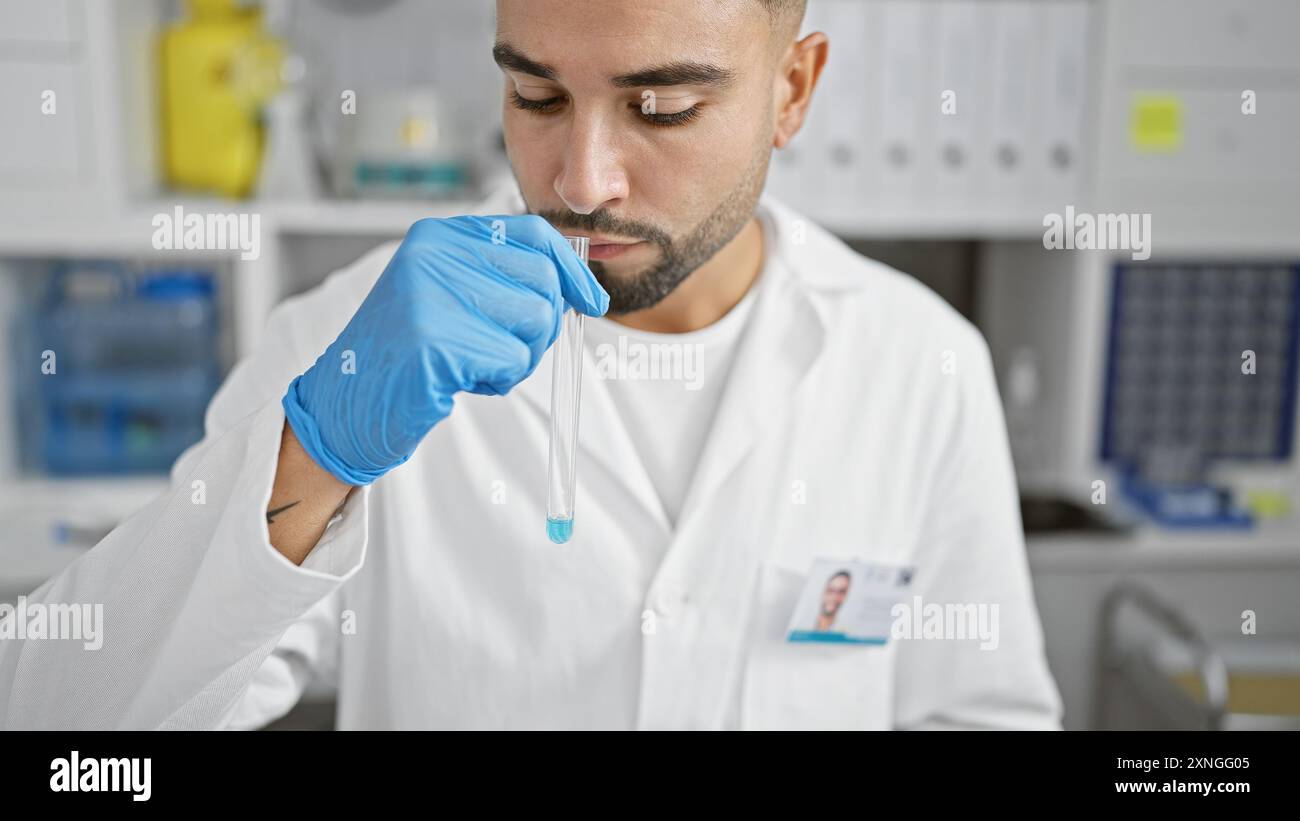 A man smelling a chemical in a test tube inside a laboratory, clad in a ...