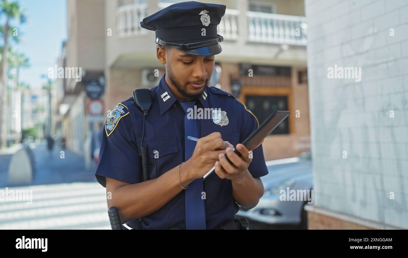 African american policeman taking notes on tablet on city street Stock ...