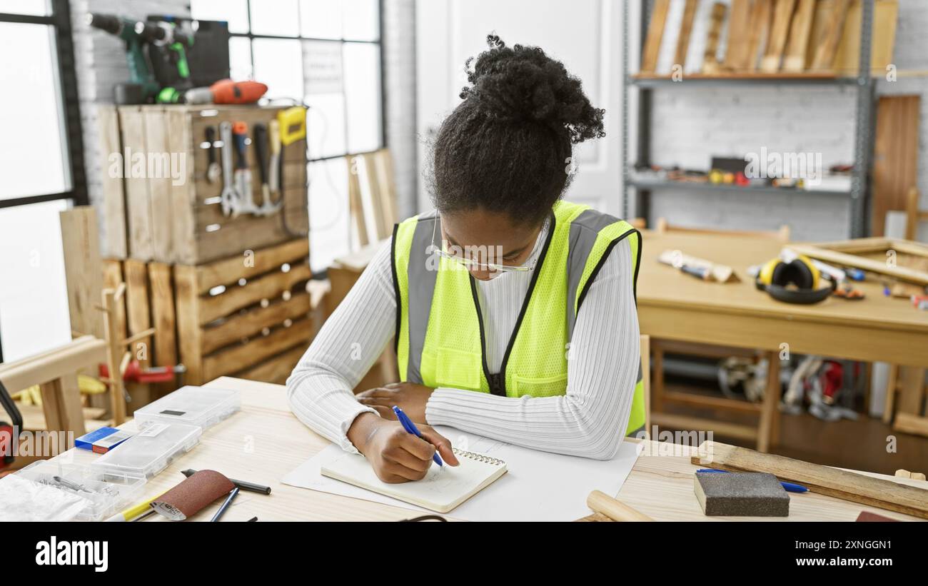 African american woman craftsman writing in notebook at carpentry ...