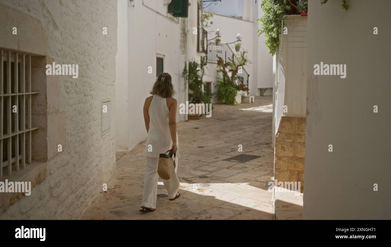 A young hispanic woman walks through the picturesque white streets of ...