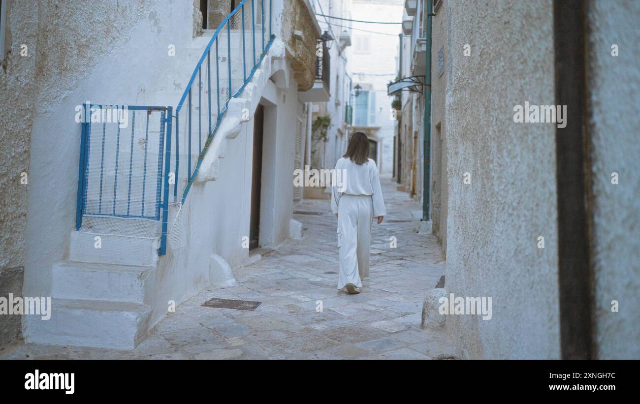 A young hispanic woman walks through the beautiful, narrow streets of ...