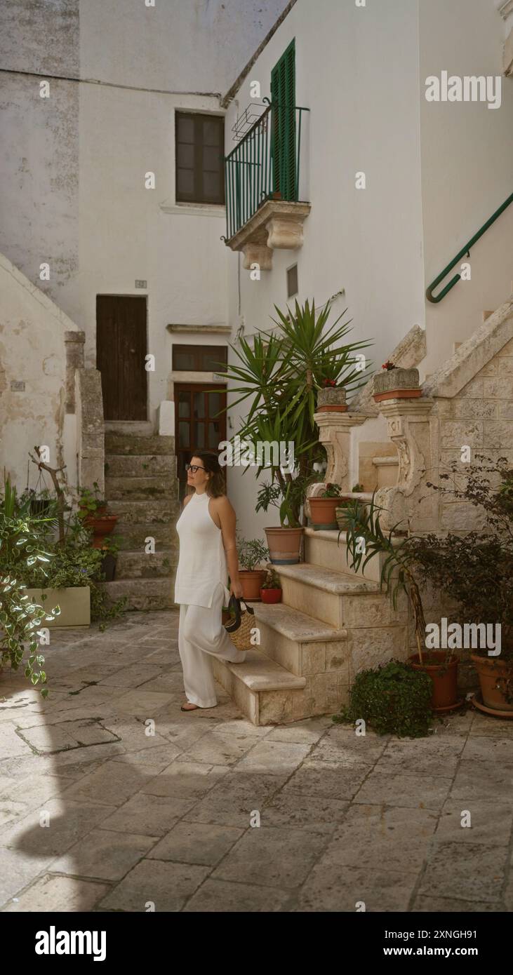 Hispanic woman in white attire stands on stone steps amidst potted ...