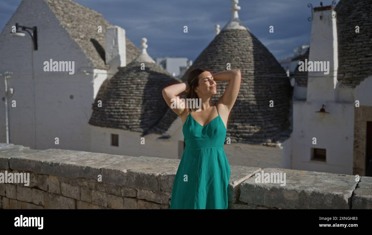 Young hispanic woman in a green dress enjoying the sun on a stone ...
