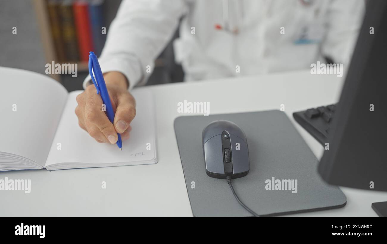 A man in a white coat writing notes with a computer in a modern clinic ...
