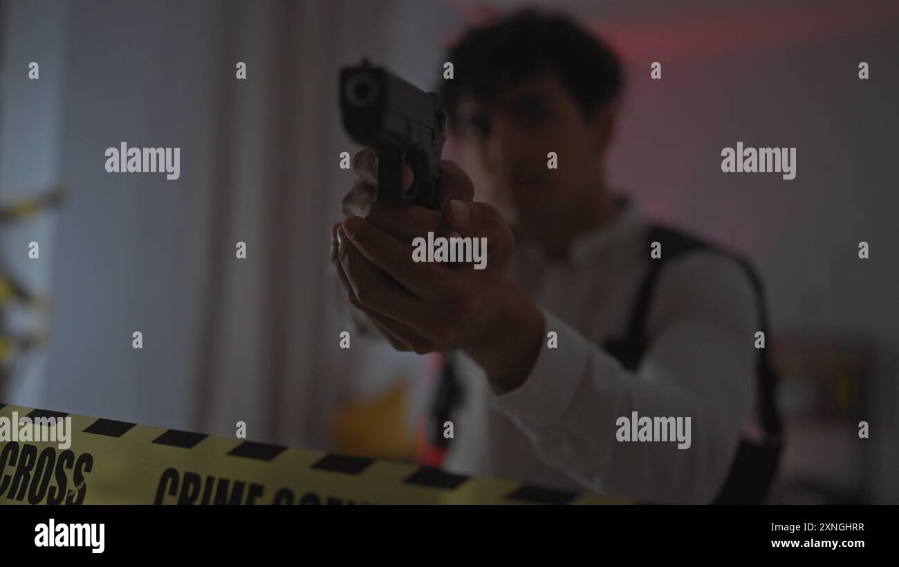 A young hispanic man pointing a gun in a dimly lit living room taped ...