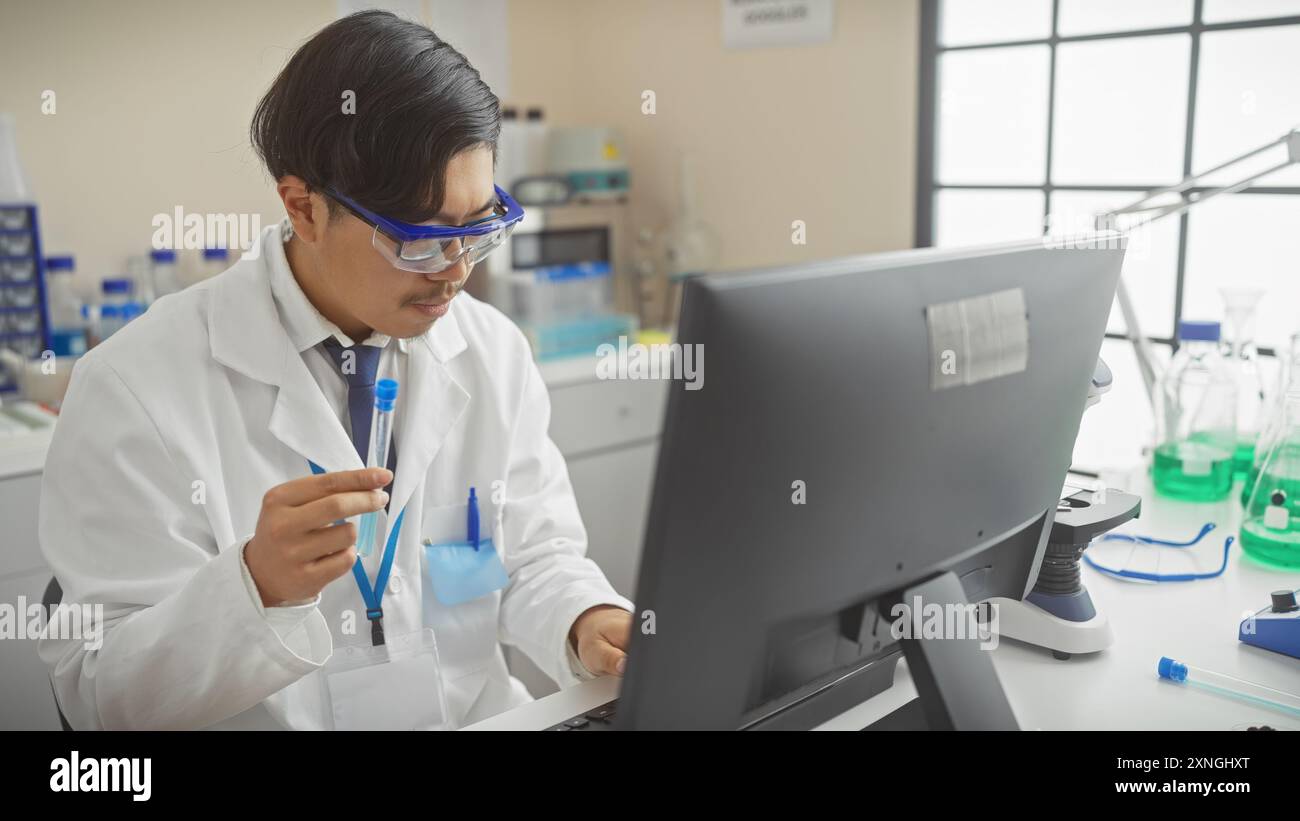 A young asian man in a lab coat conducts experiments in a modern ...