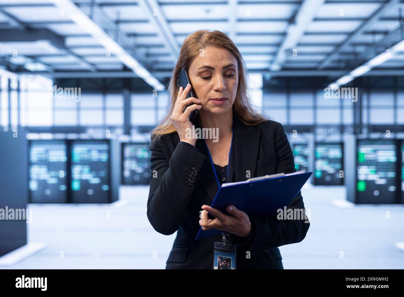 Manager maintaining accurate documentation of data center equipment, chatting on mobile phone ...