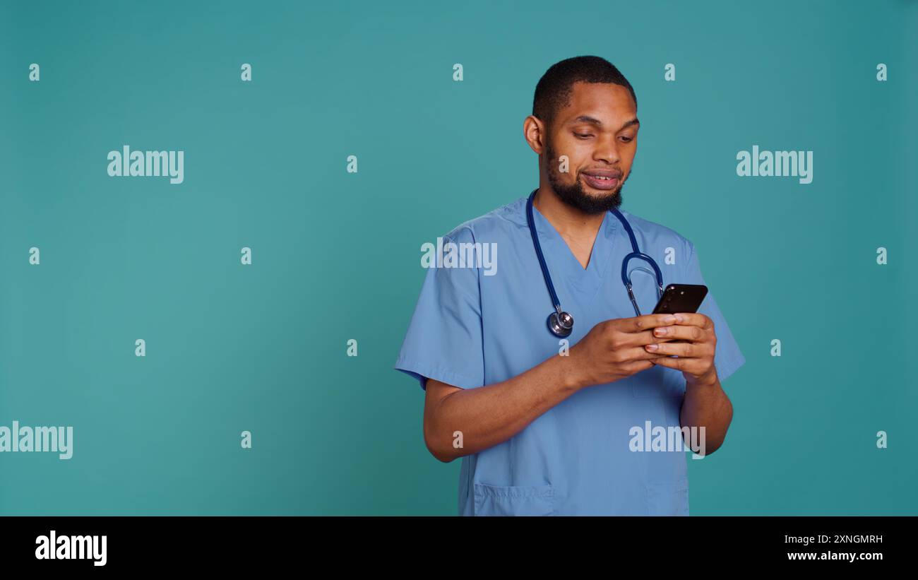 Male nurse using mobile phone to scroll on social media feed during ...