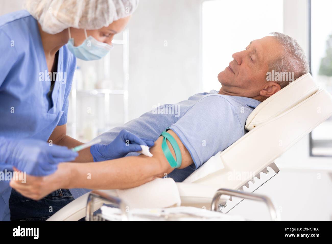Senior man lying on couch, getting intravenous injection in medical ...