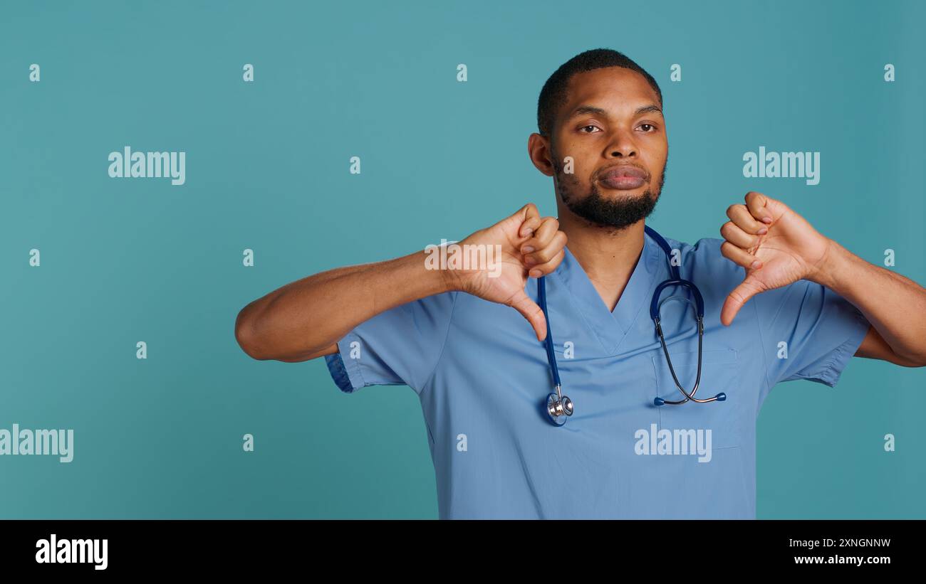 Sad african american male nurse showing thumbs down signs while at work ...
