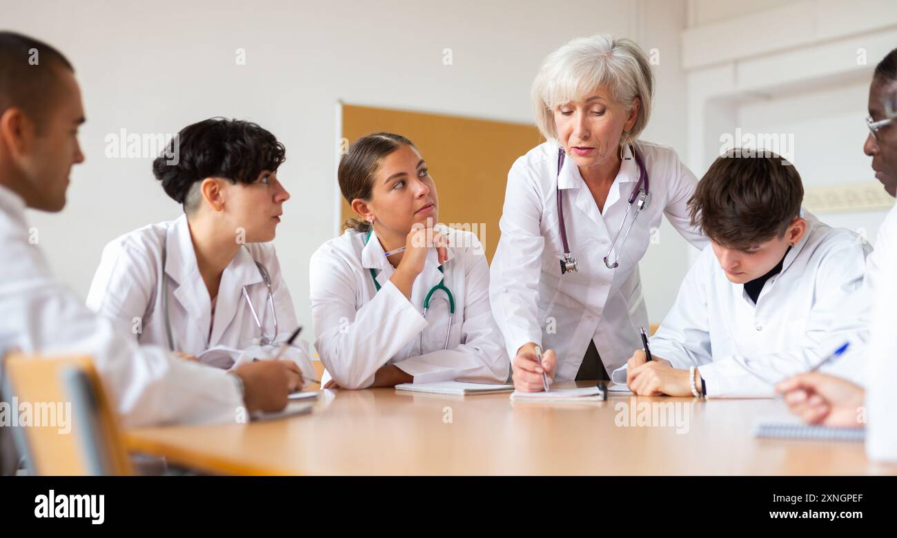 Elderly female professor of medicine giving lecture to group of ...
