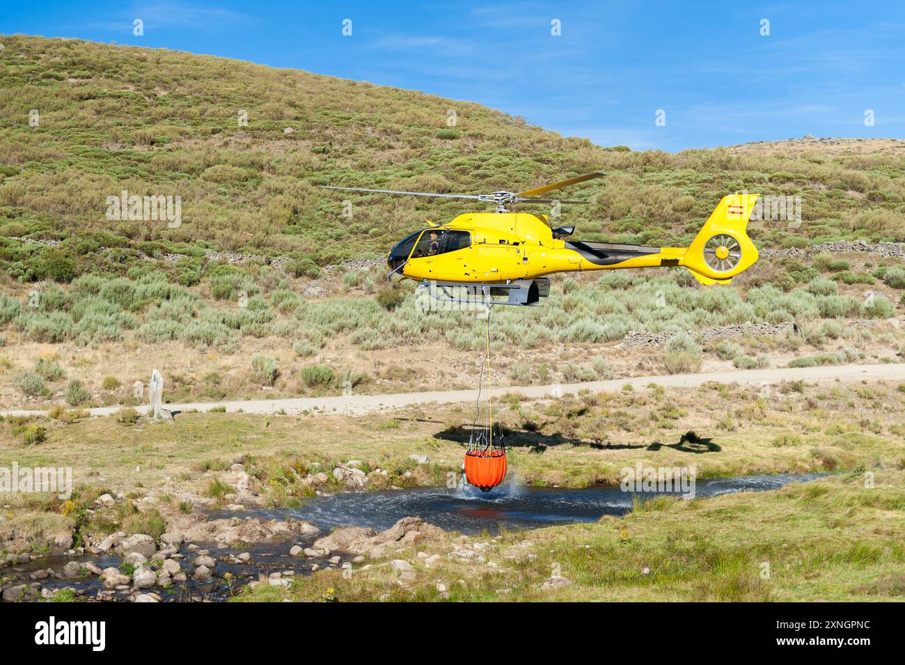 Helicopter on river bed with basket full of water Stock Photo - Alamy