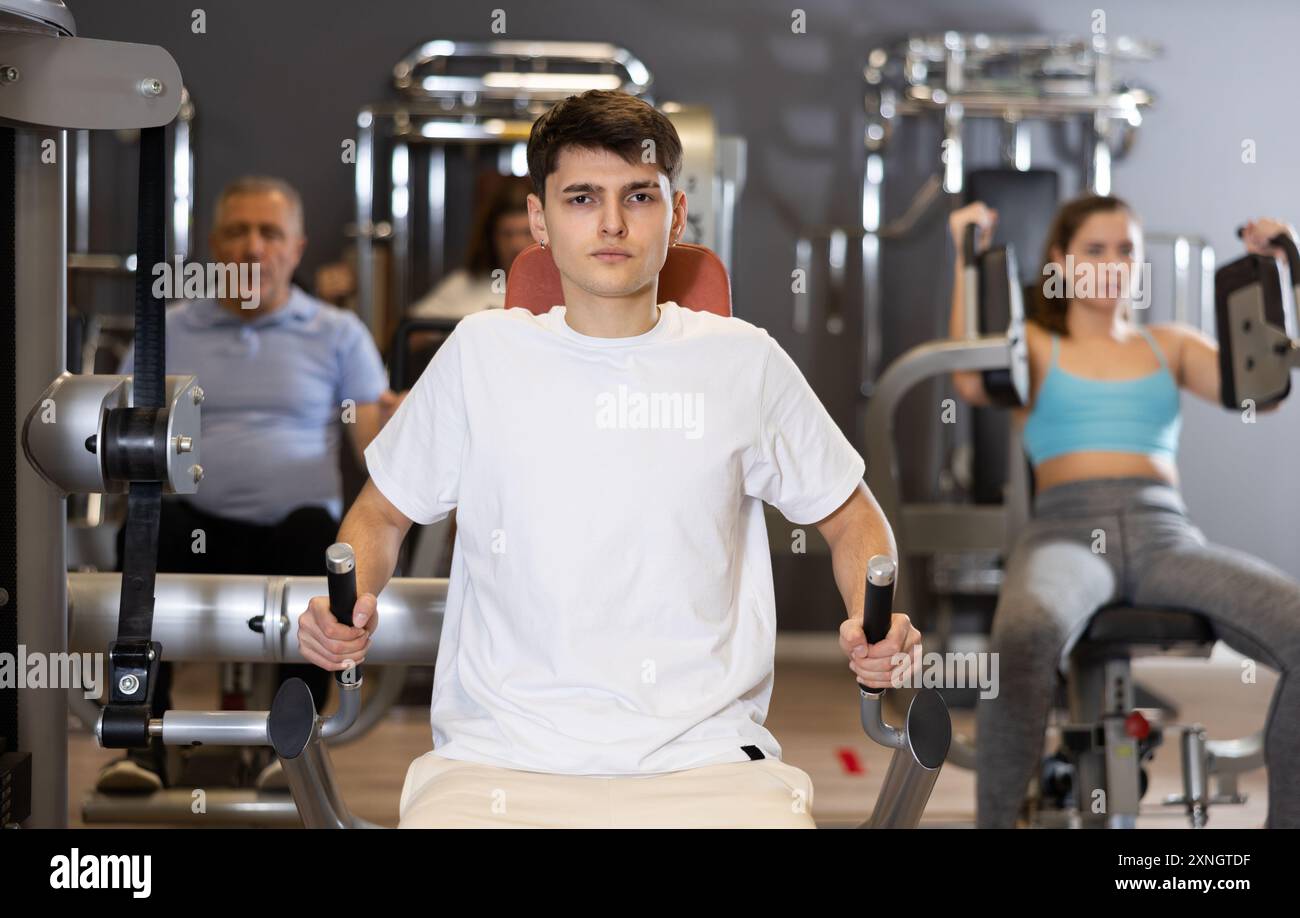Guy doing triceps press in exercise machine in gym Stock Photo - Alamy