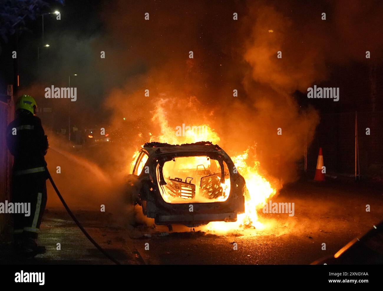 Firefighters tend to a burning police car burns as officers are ...