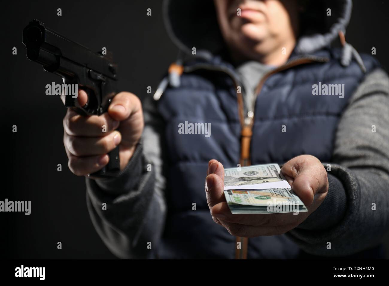 Dangerous criminal with gun holding money on black background ...