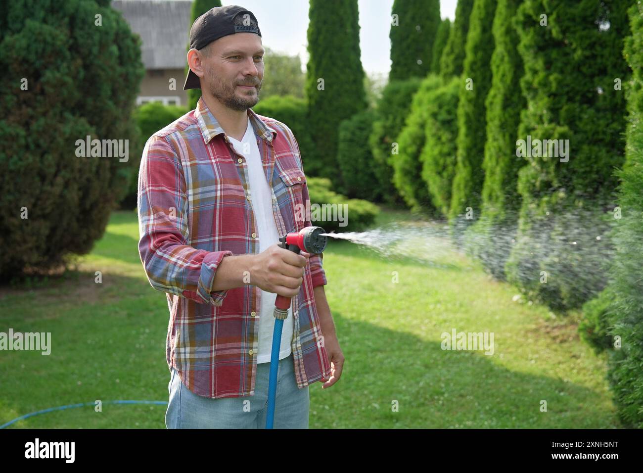 Man watering lawn with hose in backyard Stock Photo - Alamy