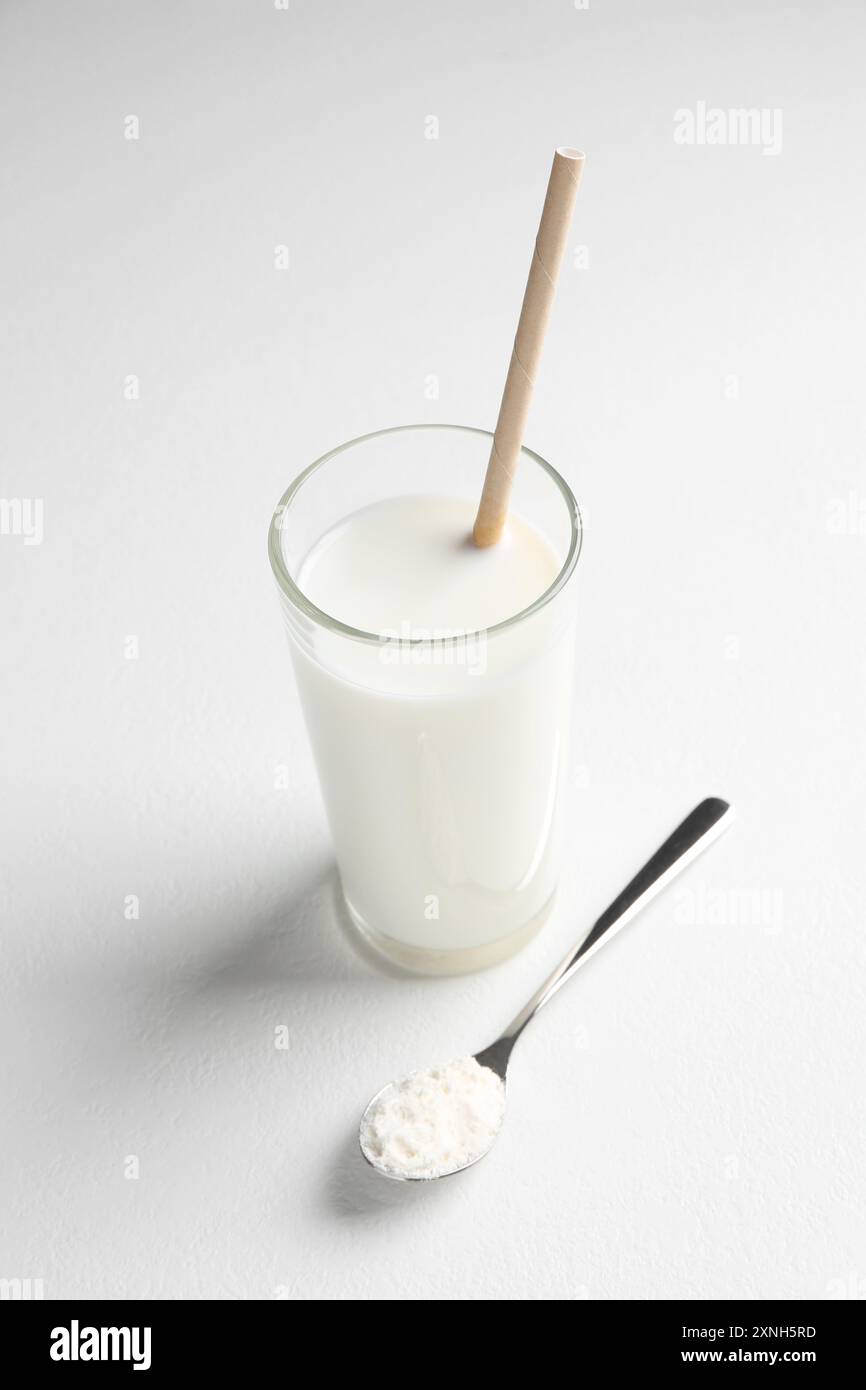 Delicious protein shake in glass and spoon with powder on white ...
