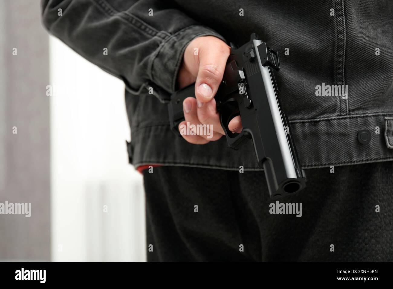 Man hiding gun behind his back indoors, closeup. Armed robbery Stock ...
