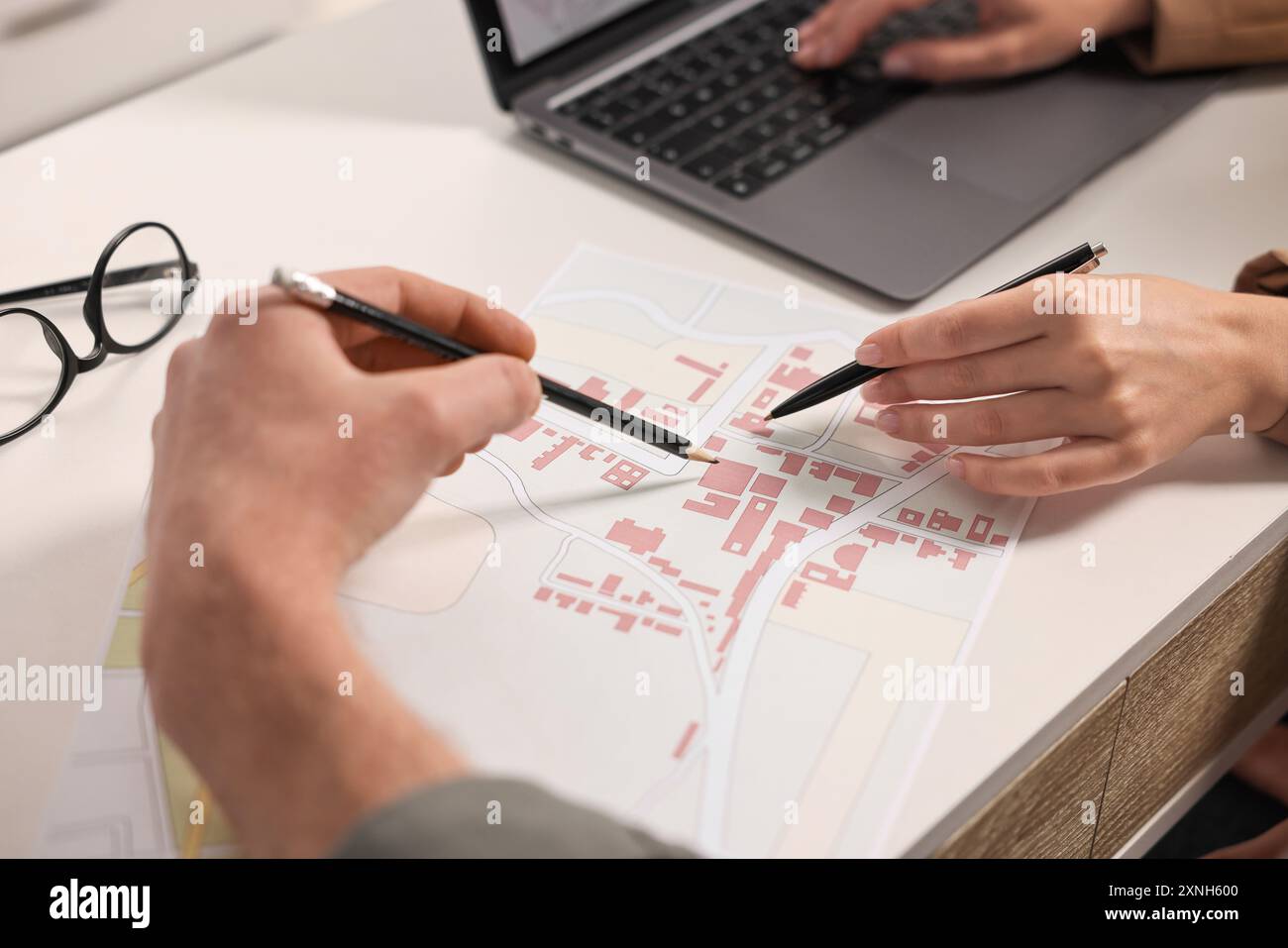 Cartographers working with cadastral map at white table in office ...