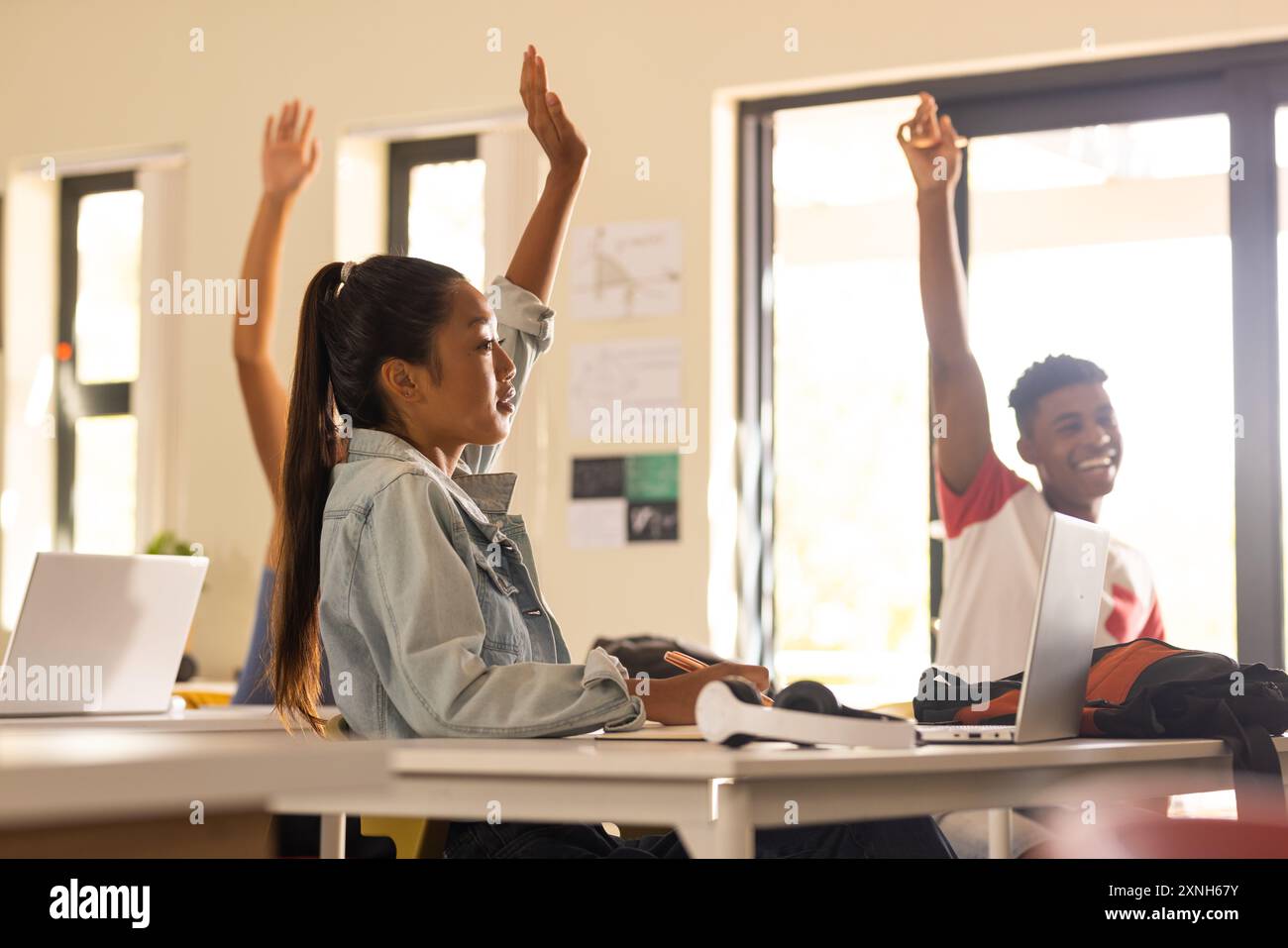 In high school, teenagers raising hands in classroom, engaging in ...