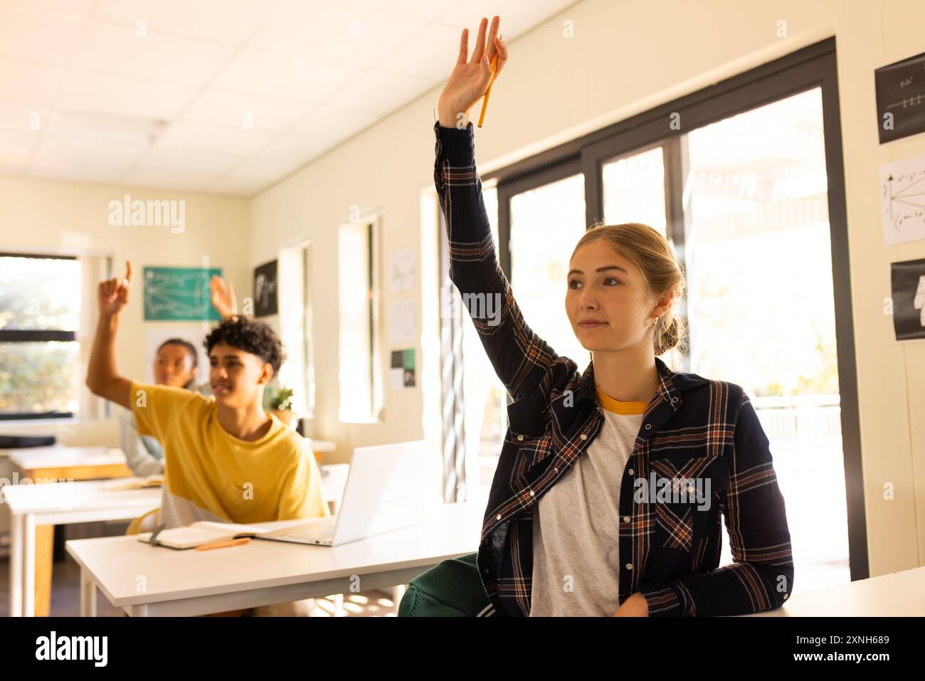 In high school, students raising hands to answer question in classroom ...