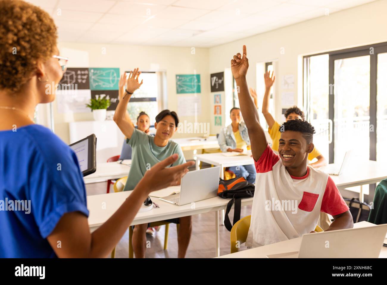 In high school, students raising hands and engaging with teacher in ...