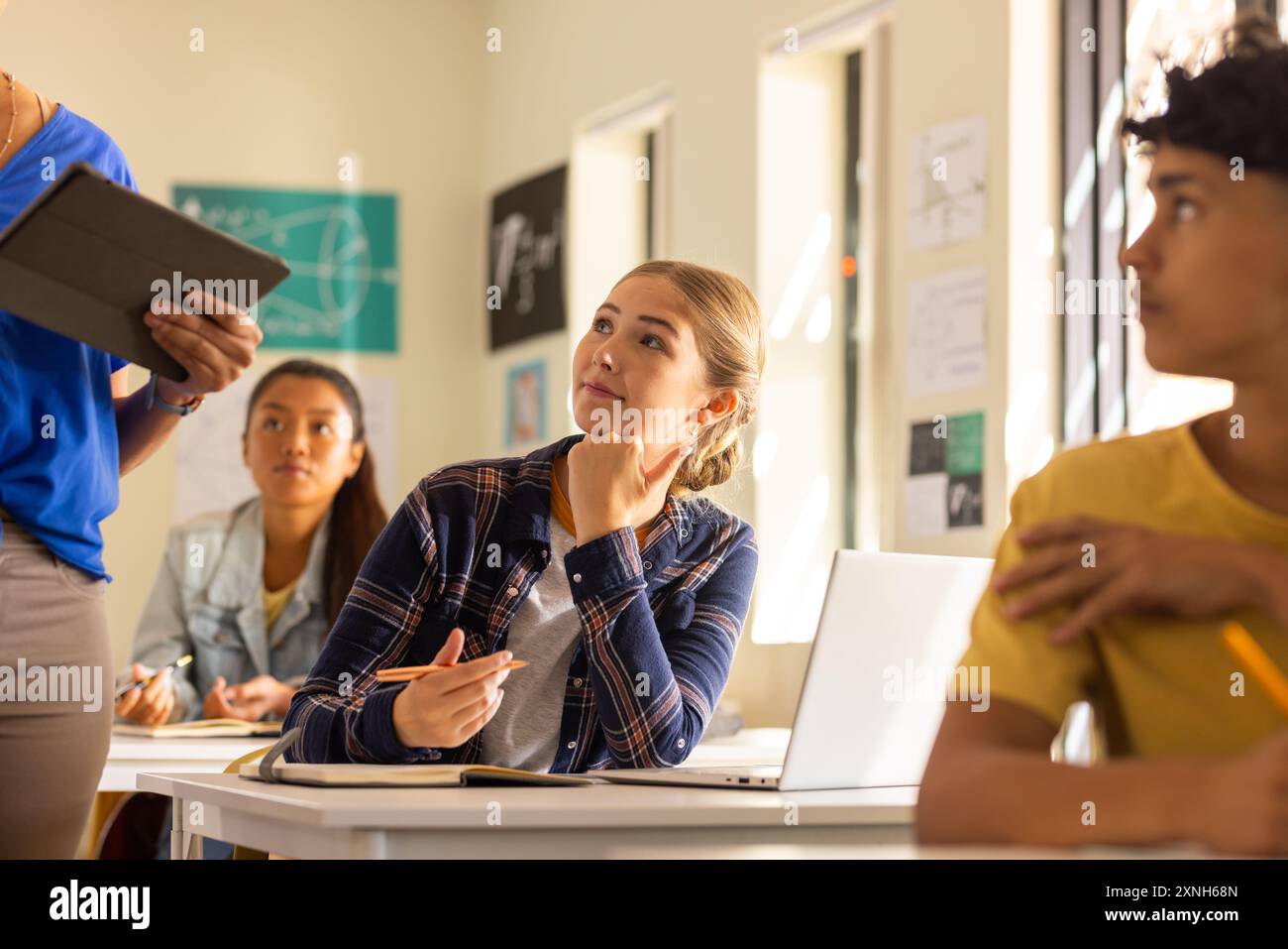 In high school, students listening to teacher, using laptop and taking ...