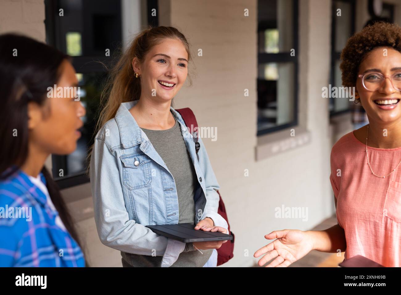 Talking with friends, teenage girls holding books and smiling at high ...