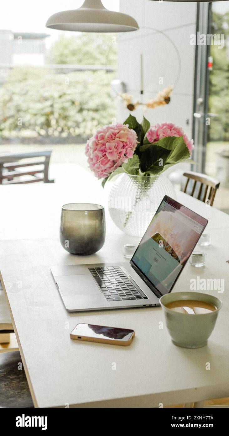 Bright workspace with a laptop, flowers, and coffee on a table. Ideal ...