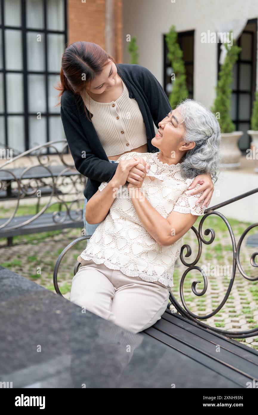 A caring, lovely Asian granddaughter is hugging her grandma, spending ...