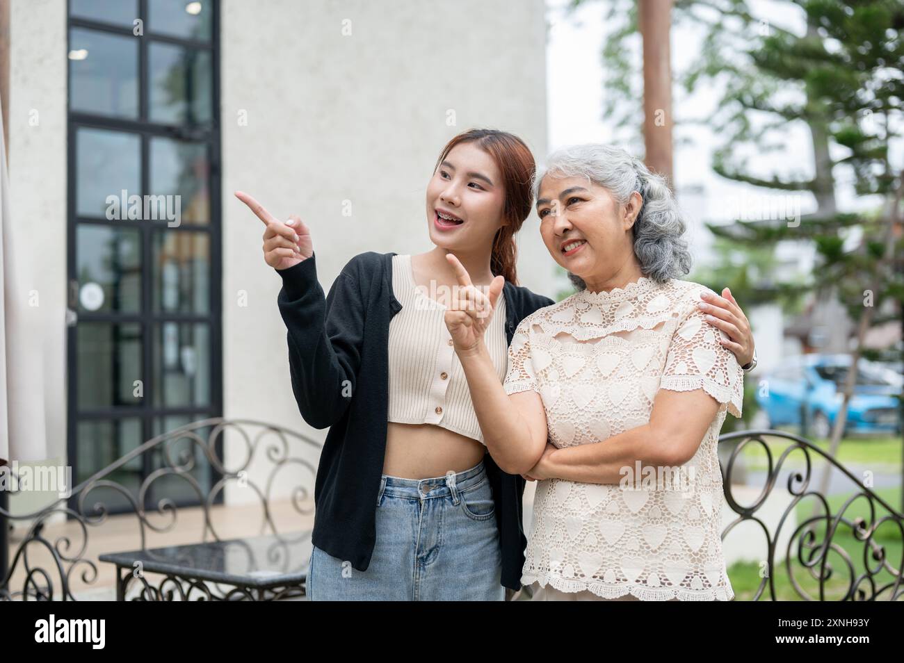 A happy, mature Asian grandma is gazing at the view in the garden with ...