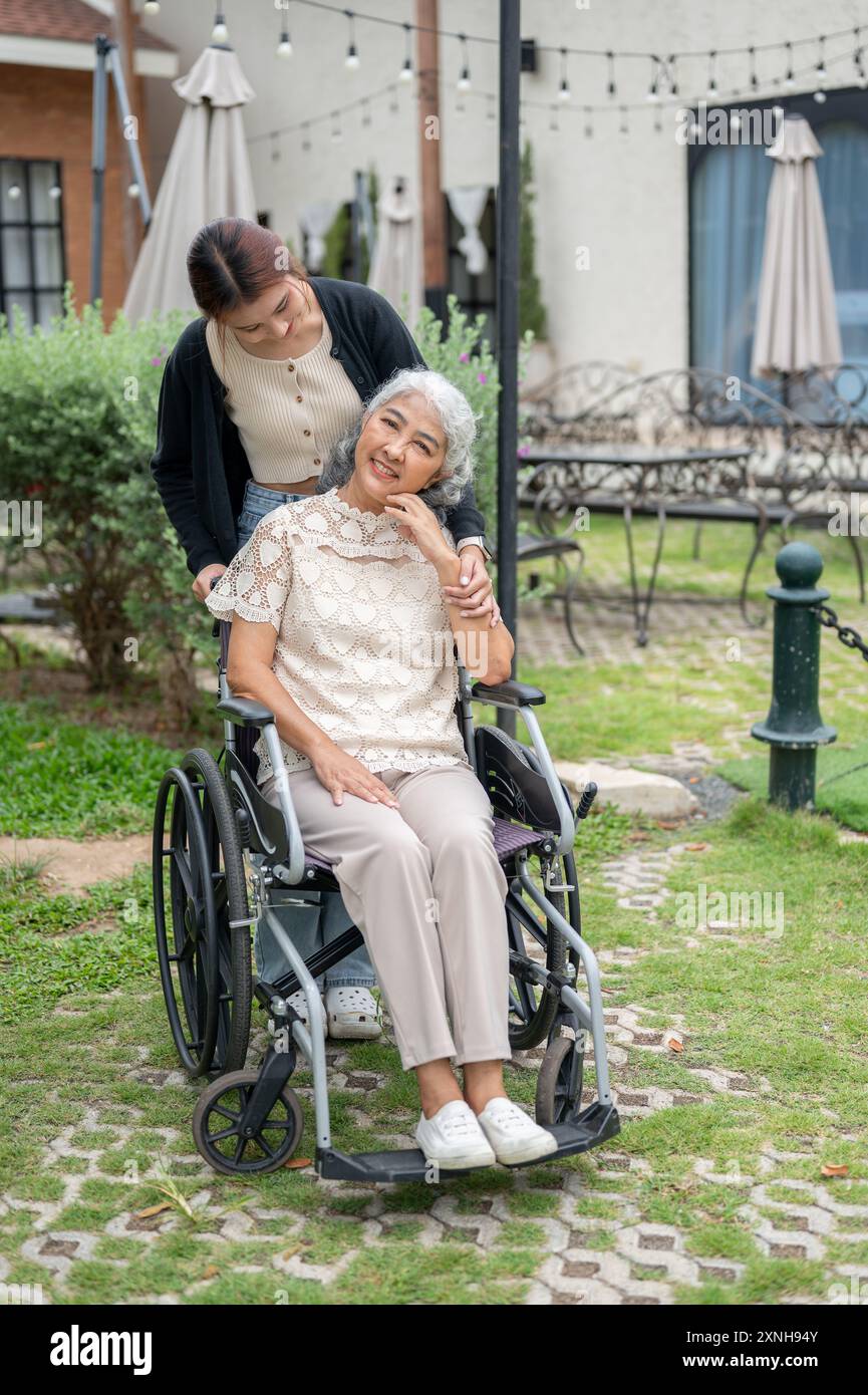 A smiling Asian senior grandma is on a wheelchair with a lovely ...