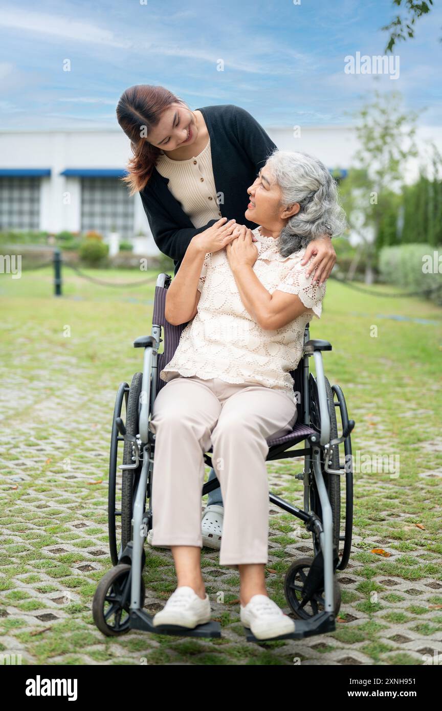 A smiling Asian senior grandma is on a wheelchair with a lovely ...