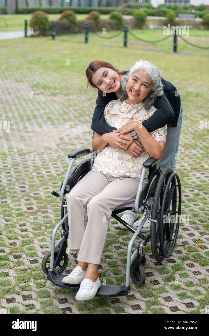A lovely Asian granddaughter is hugging her grandma, who is in a ...