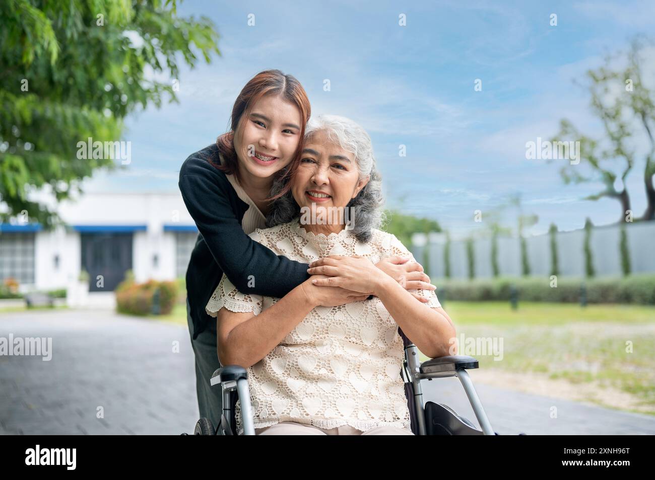 A happy, positive retired Asian grandma in a wheelchair is in a park ...